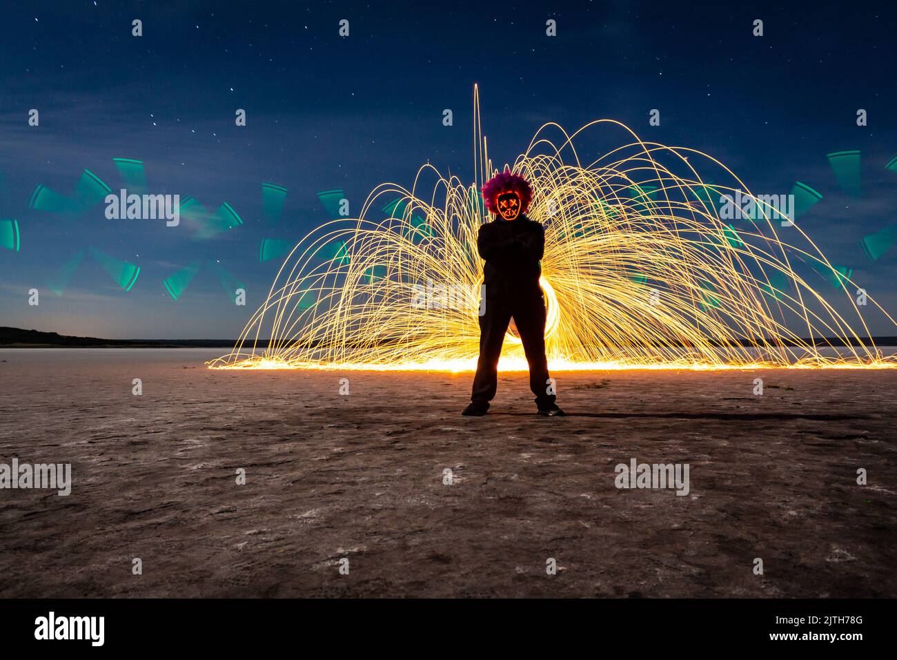 Silhouette of a masked man standing in front of a glowing steel wall ...