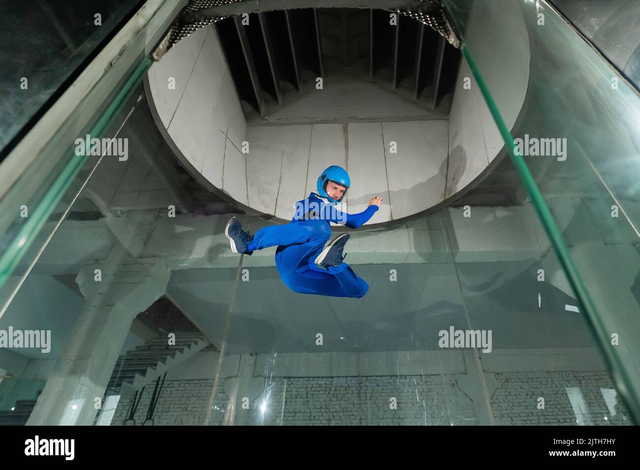 A man in overalls and a protective helmet enjoys flying in a wind ...