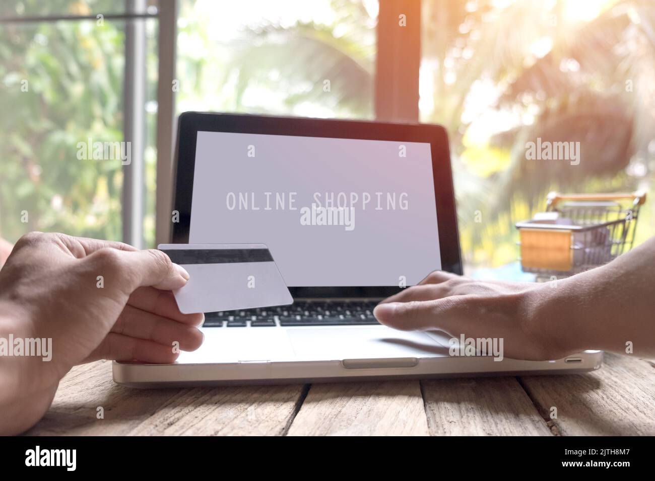 Man holding credit card in hand and entering security code using laptop ...