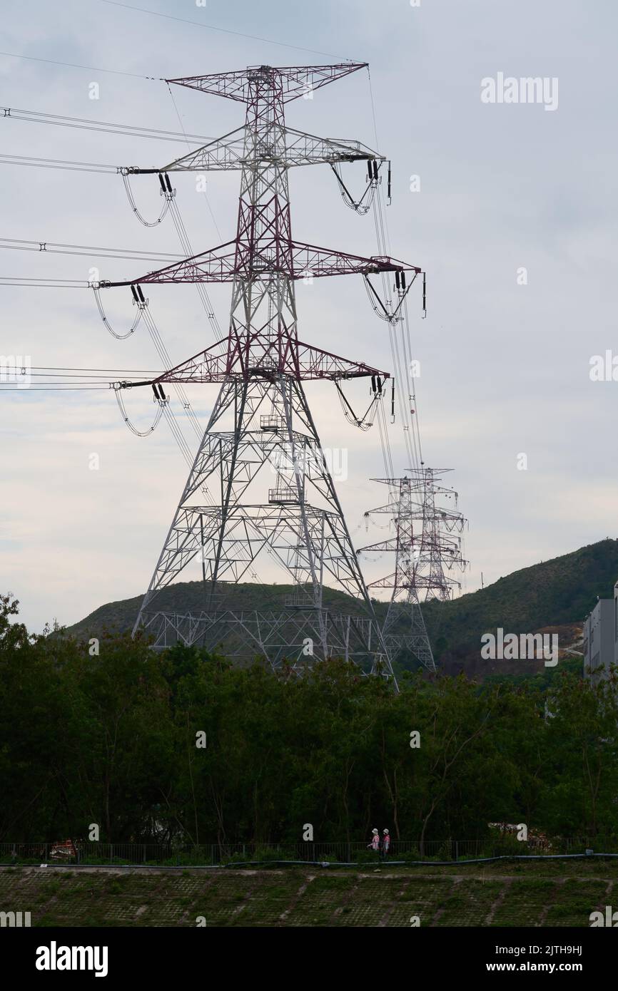A vertical shot of electric power towers in a green field in Sheung ...