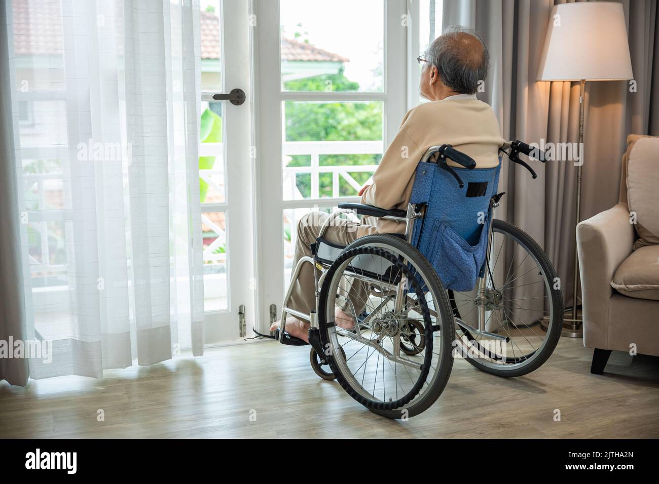 Asian senior man disabled sitting alone in wheelchair looking through ...