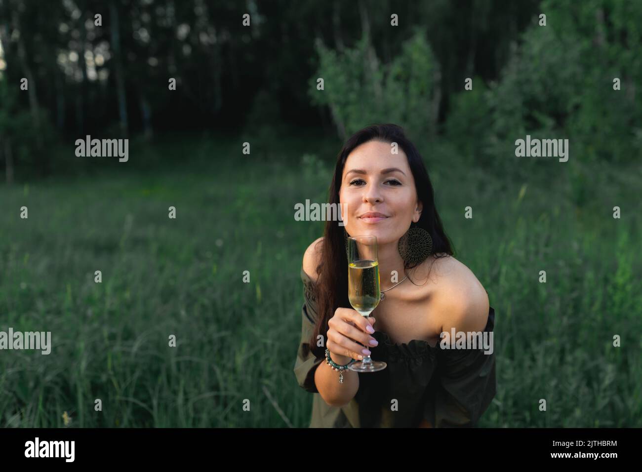 An attractive woman with a glass of champagne on a forest plot in the ...