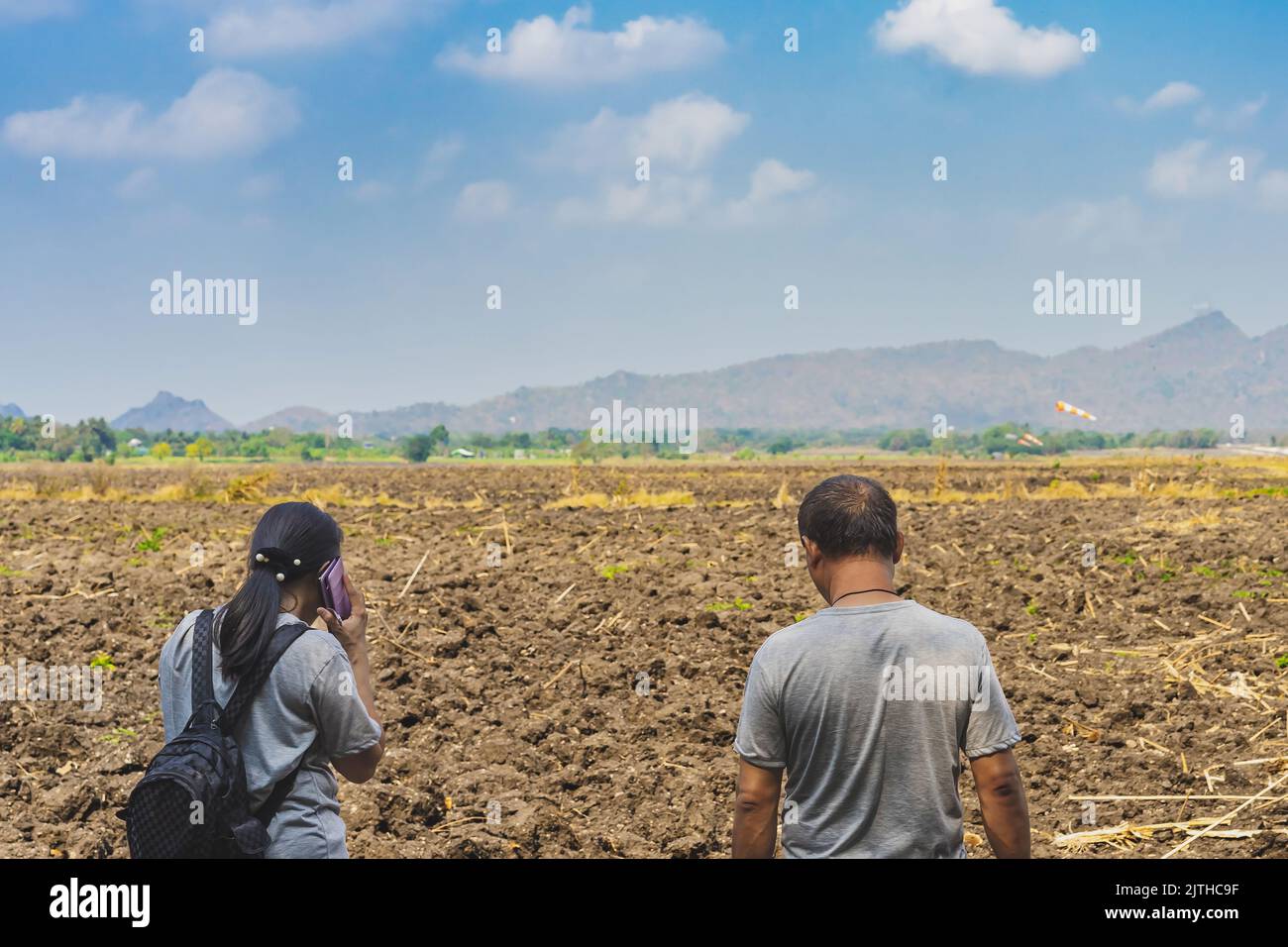 Back view of Asian couple farmers discuss soil quality for farming in soil field. Lovers ...