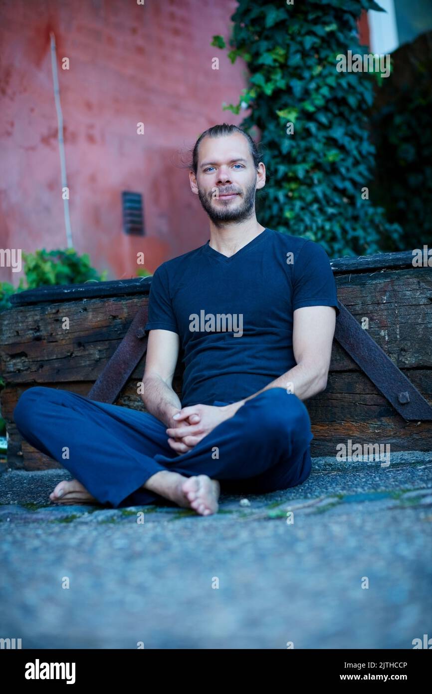 Enjoying a quiet moment. Portrait of a man sitting against a wall ...