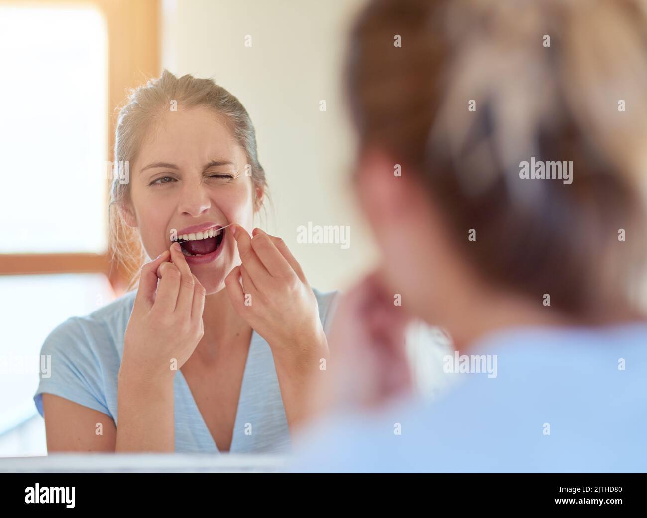 Getting Rid Of All Her Plaque A Young Woman Flossing Her Teeth In A
