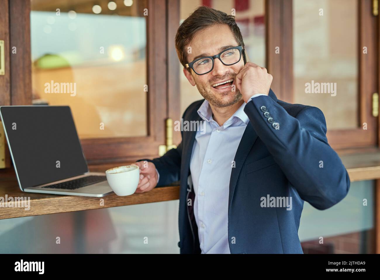 Working from my favourite cafe. a young businessman making a phonecall ...