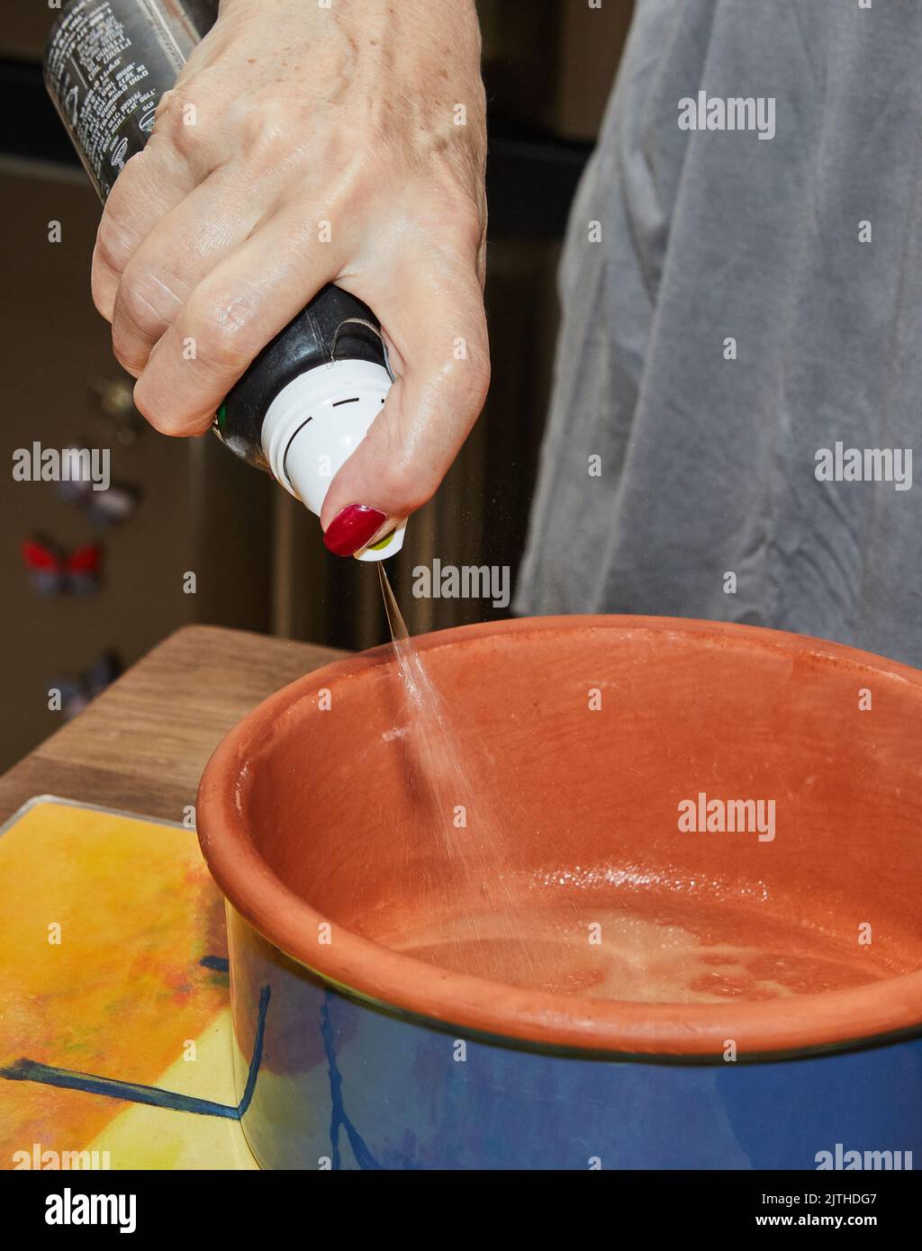 Chef sprays oil on ceramic mold for making Potato Gratin Stock Photo ...