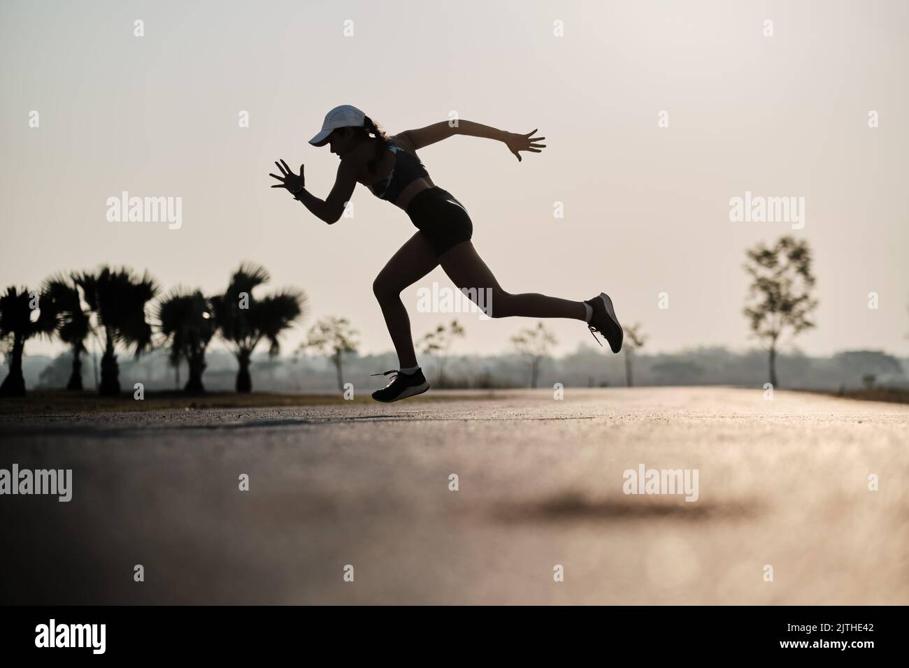 A silhouette of a southeast Asian woman running in a public park in the ...