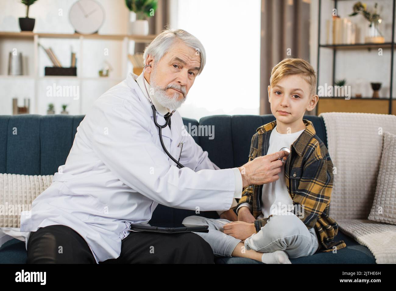 Close up of sick child boy sitting on the couch, while caring confident ...