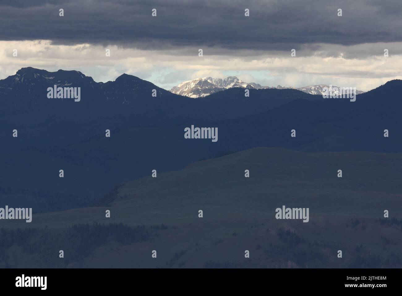 Mountain range covered in shadows, with sunlit mountains in background ...