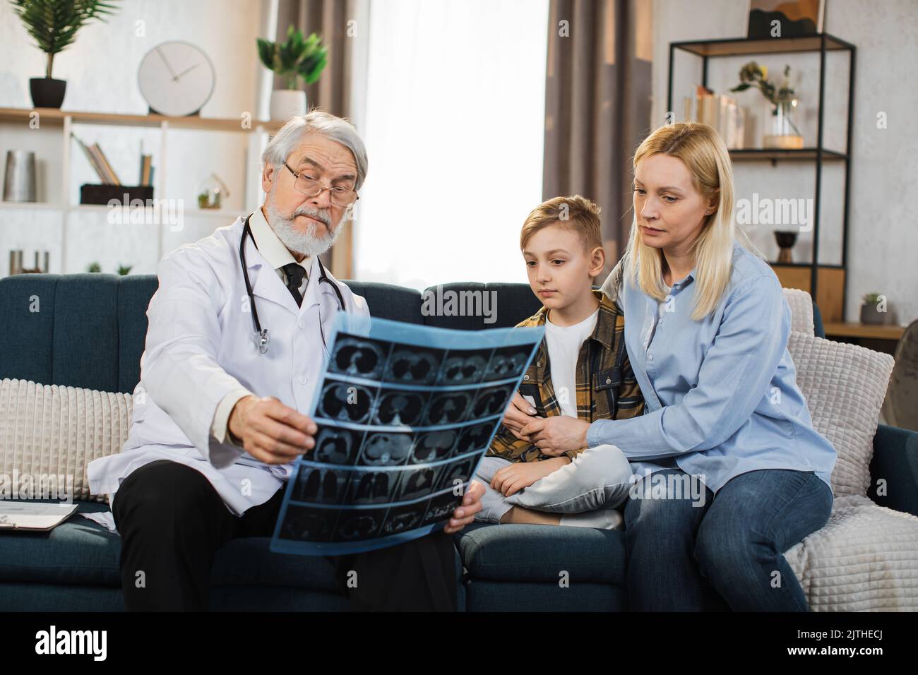 Senior male doctor, sick little boy and his mom looking at x-ray scan ...