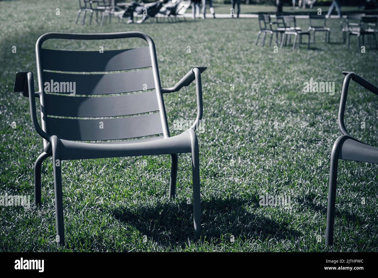 patio chair standing on grass of empty manicured lawn at dusk. Narrow ...