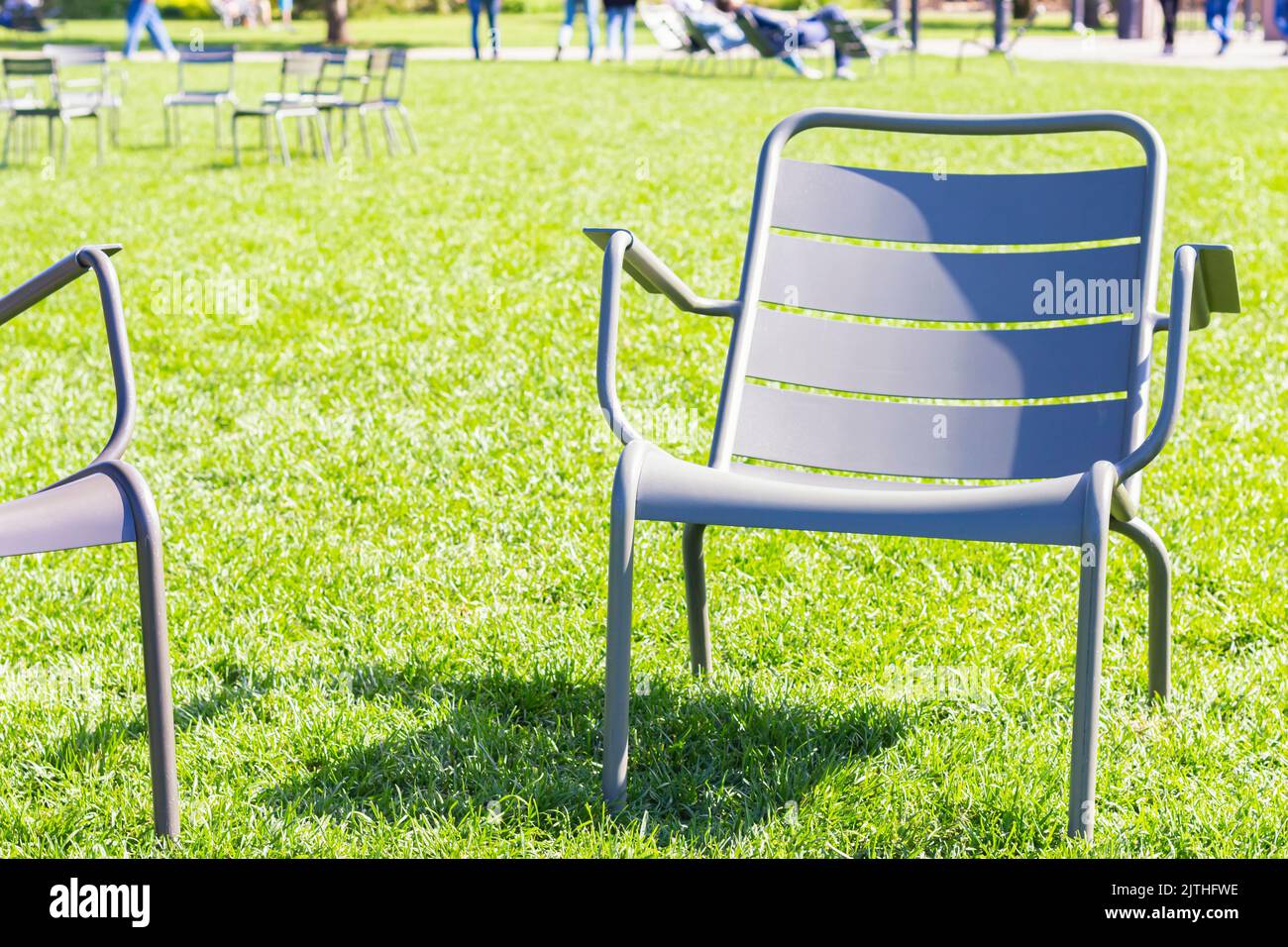 One gray metal outdoor patio chair on empty manicured sunny bright ...