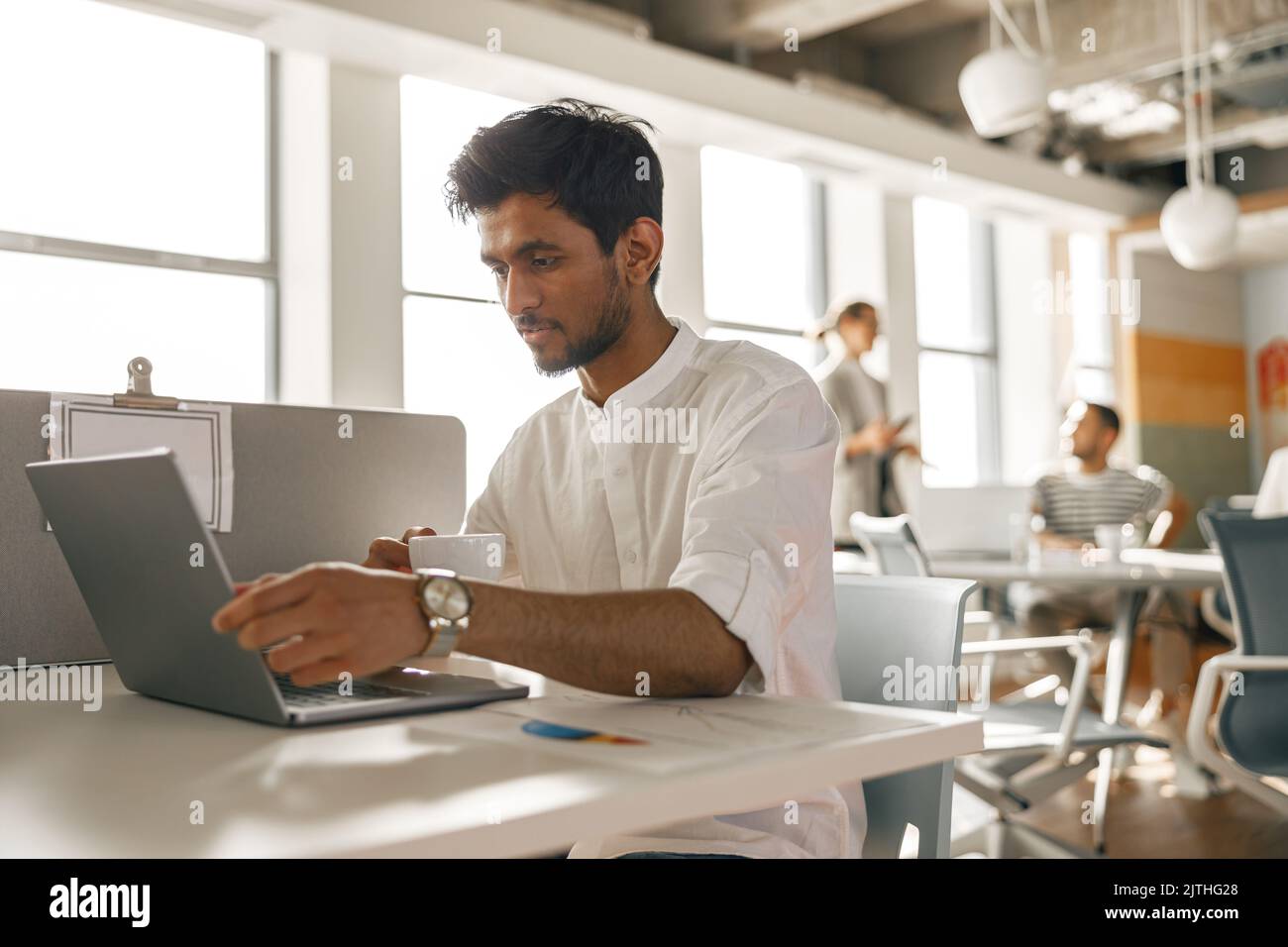 Businessman working laptop while sitting in modern office on colleagues ...