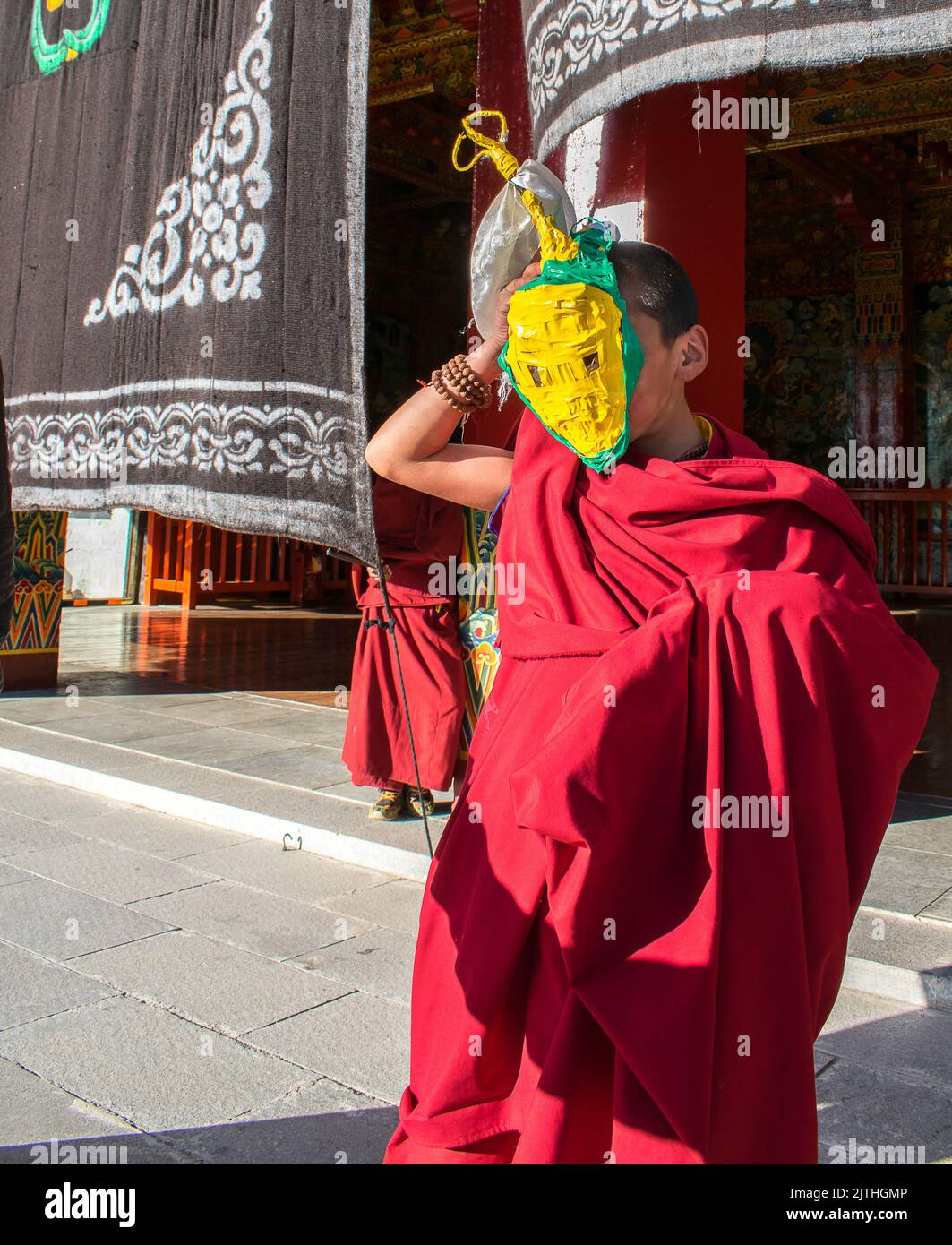 Young novice Tibetan Buddhist monk wearing red robes , welcoming ...