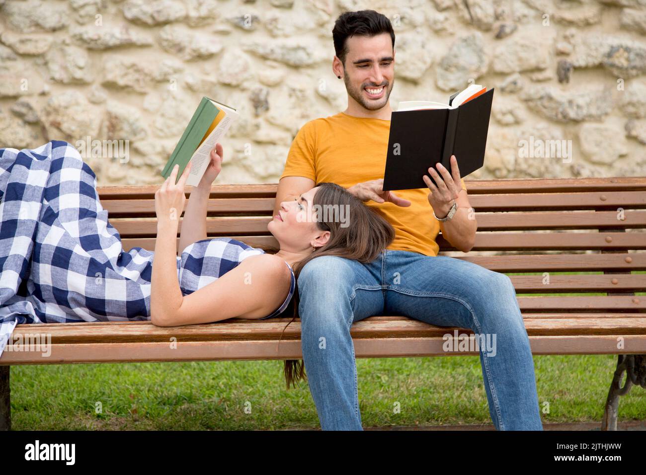 Happy lovers reading books together in a bench of a park Stock Photo ...