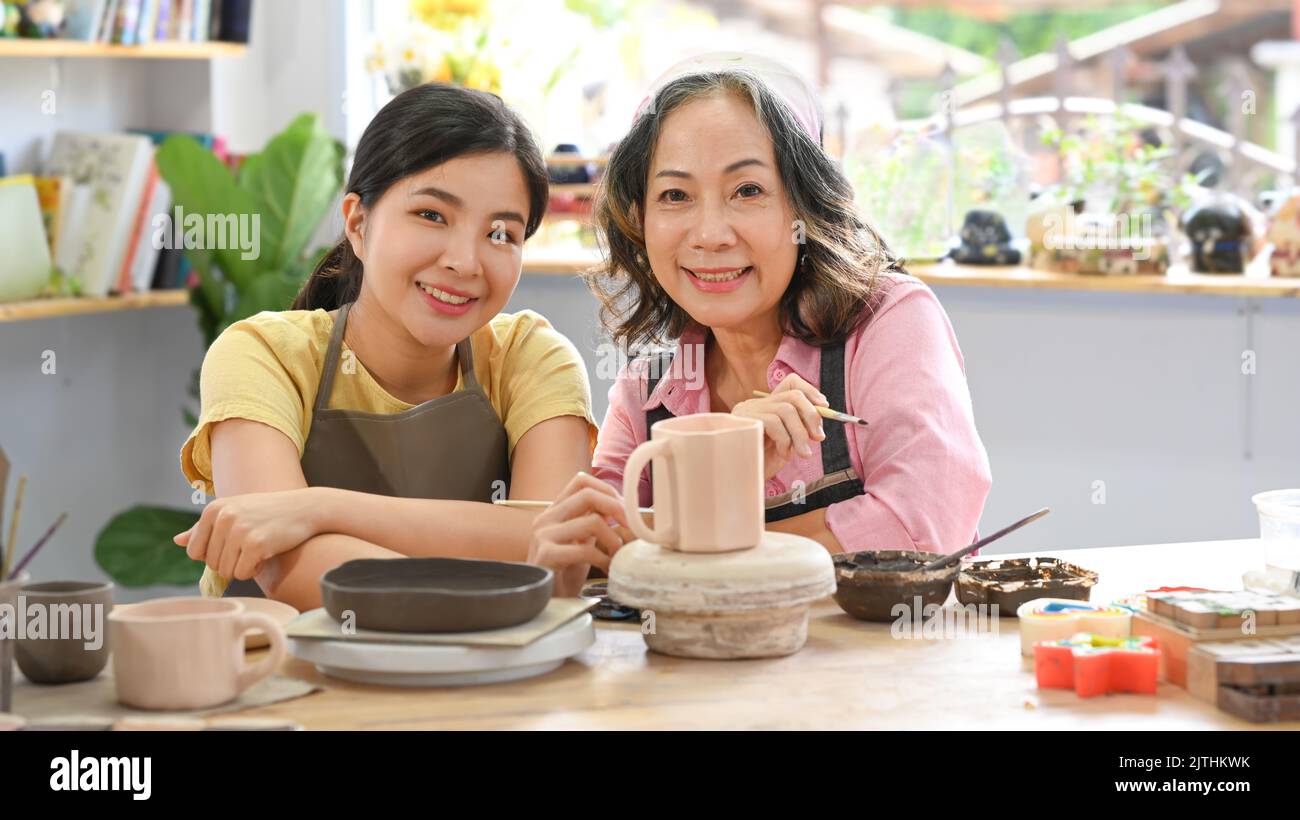 Happy young woman and middle aged woman creating handicraft crockery in ...