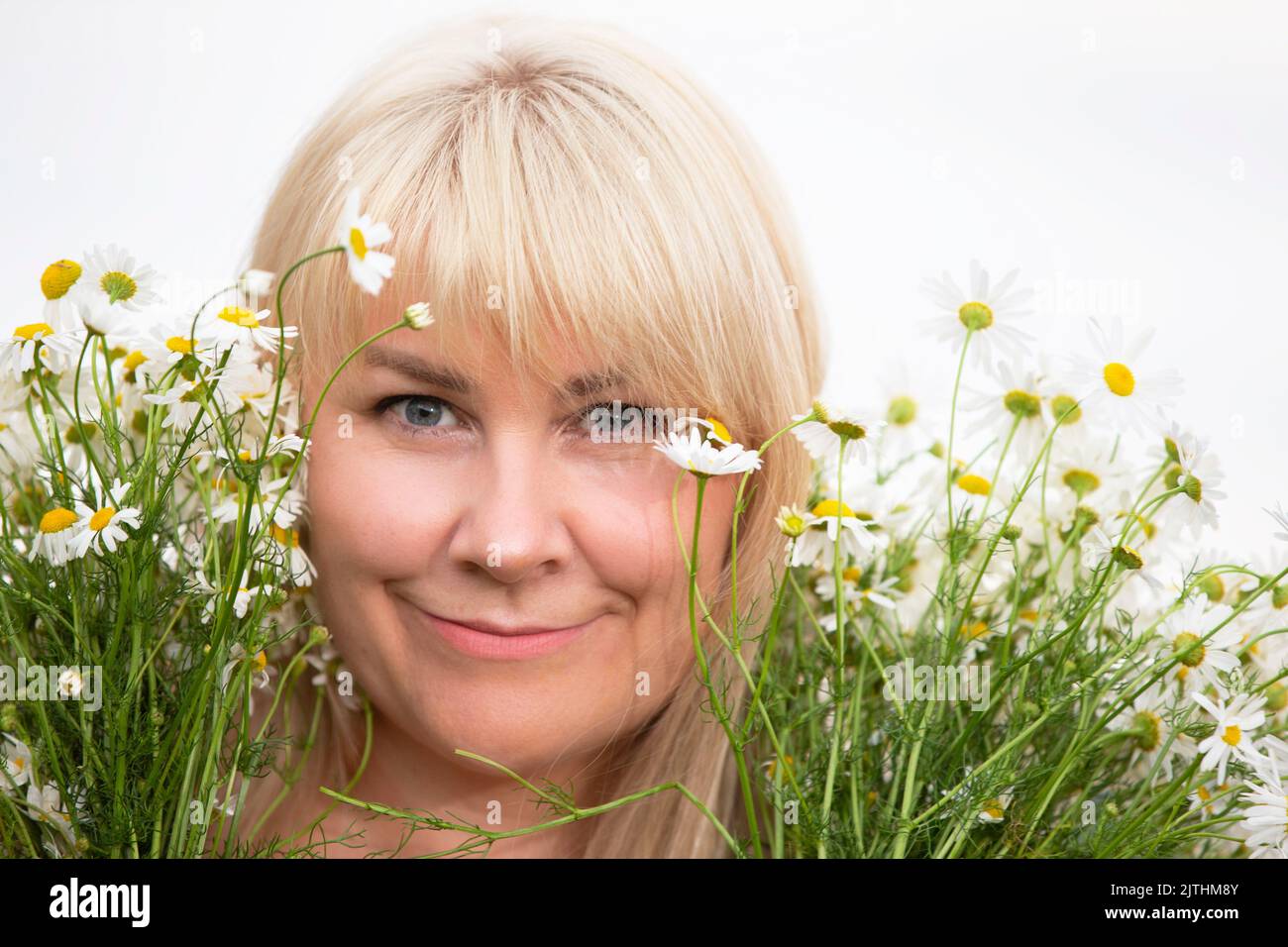A beautiful plus size woman with white hair holds a bouquet of daisies ...