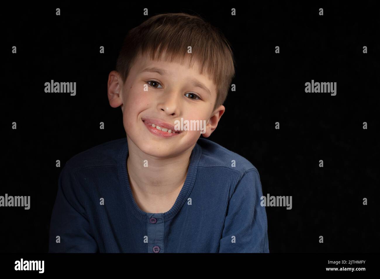 Portrait of a ten-year-old boy on a dark background. The child looks ...