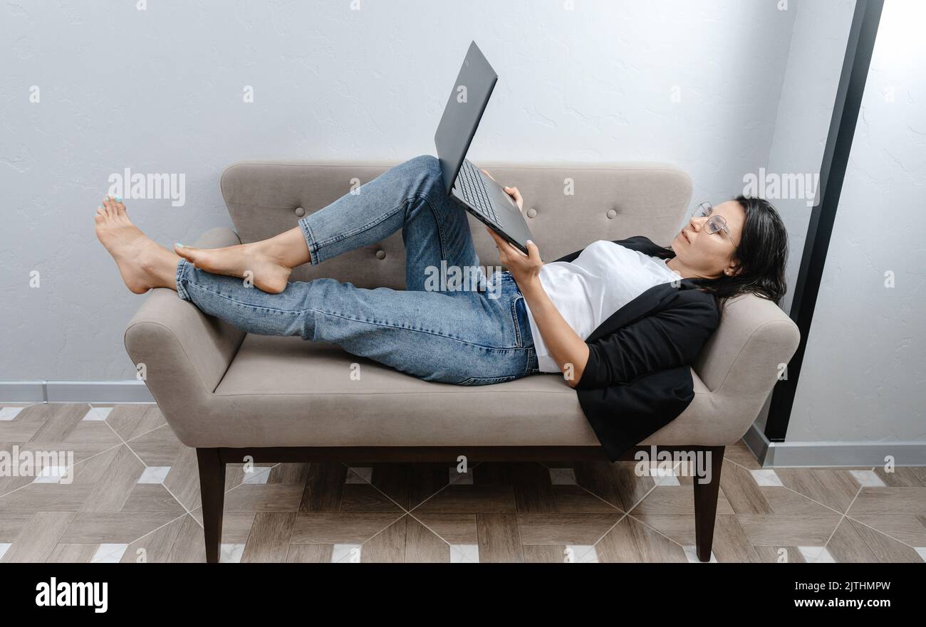 Happy calm female employee working at her laptop in the comfort of her ...