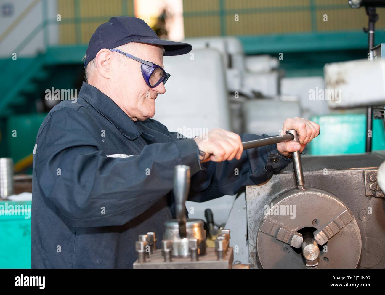 Turning production An elderly man works at a lathe. Turning works Stock ...