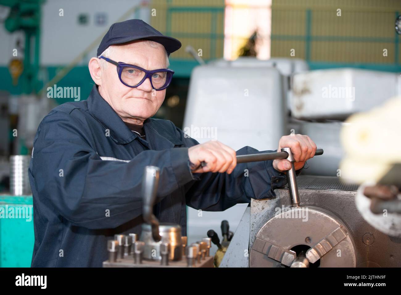 Turning production An elderly man works at a lathe. Turning works Stock ...