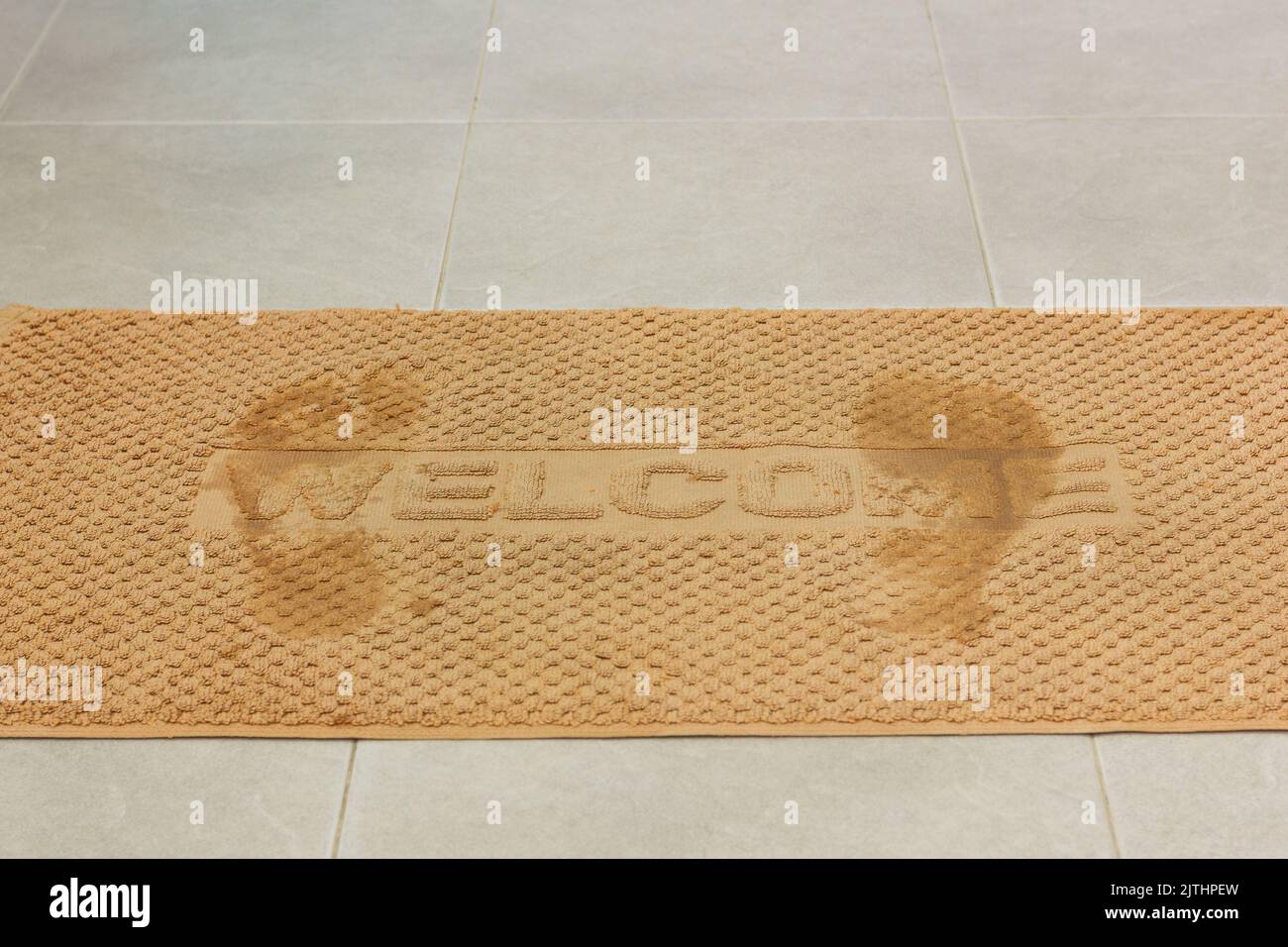 Wet footprints on bath towel with welcome sign on the bathroom floor ...