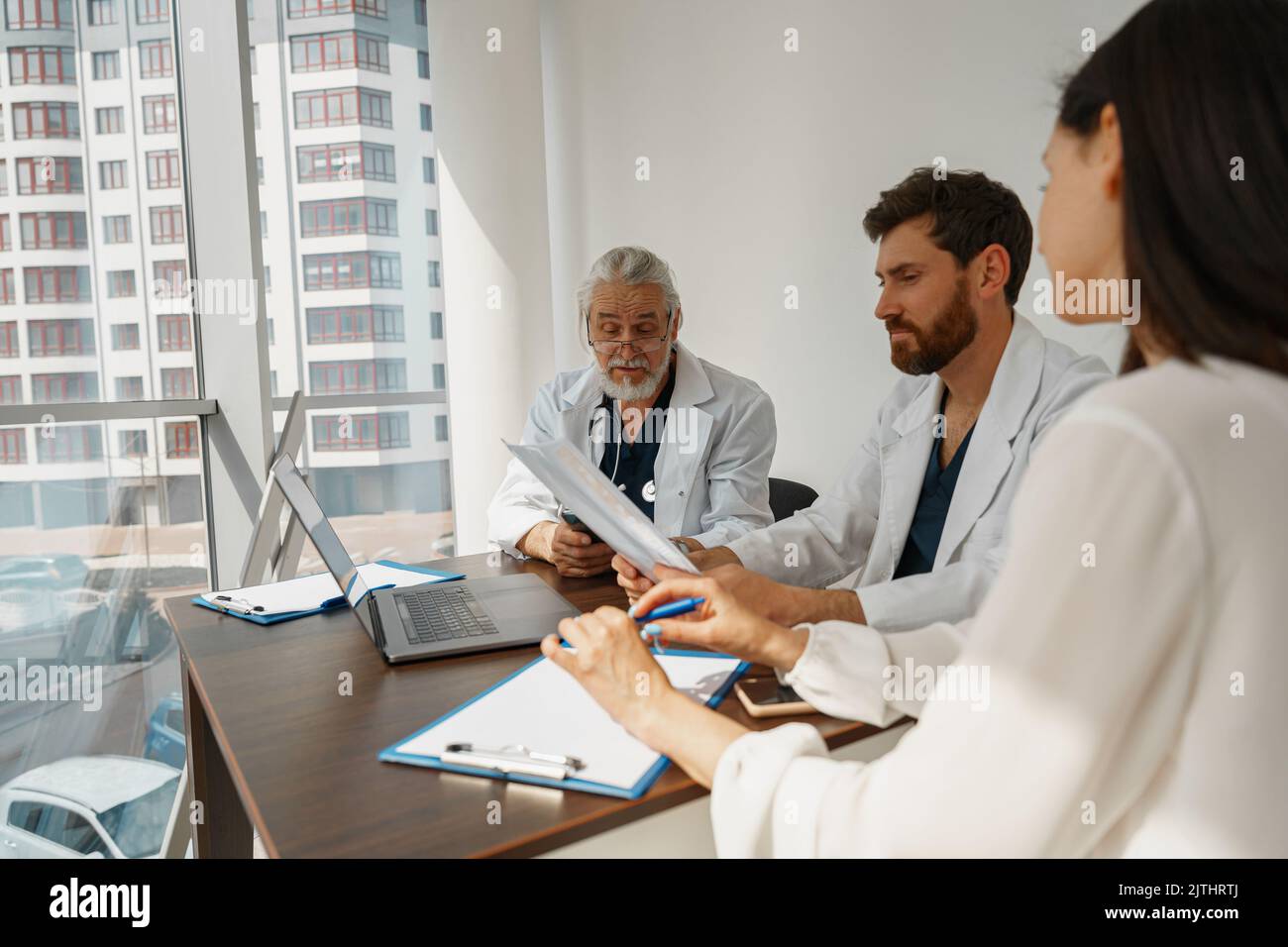 Two doctors in white uniform consult female patient at meeting in ...