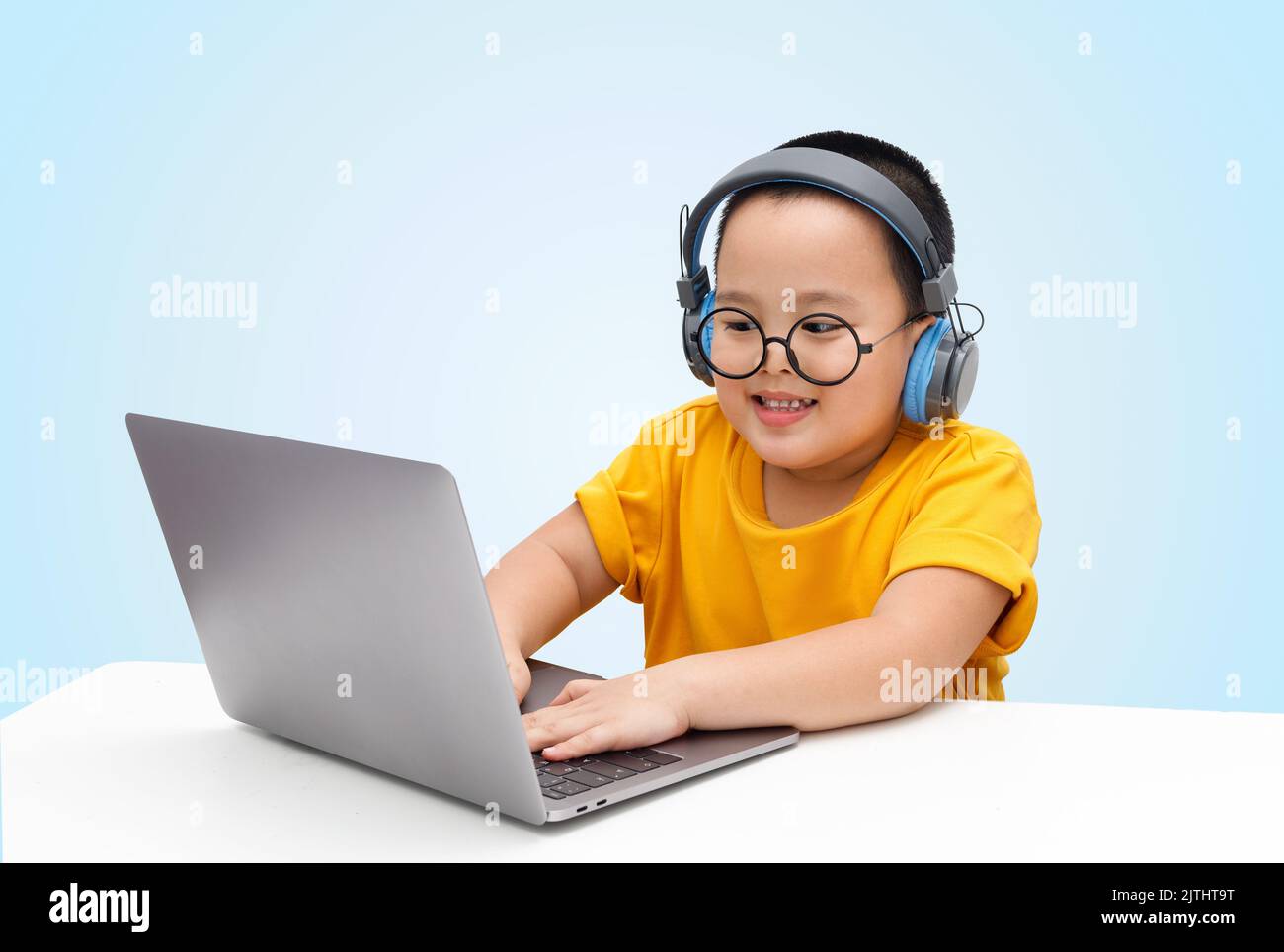Little boy wearing headphones using laptop, happy learning, listening ...