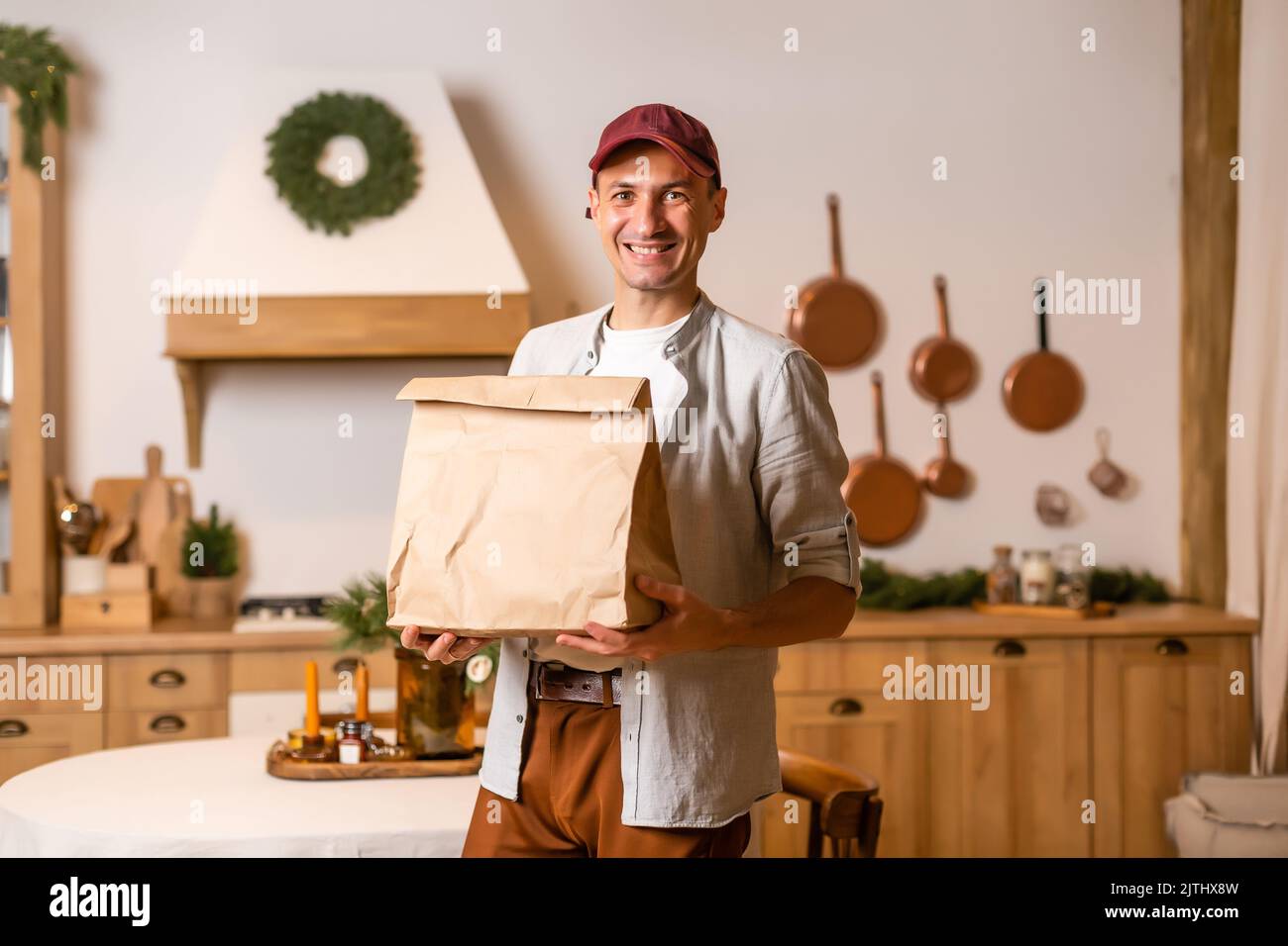 a delivery man with a package of food stands in a Christmas interior ...