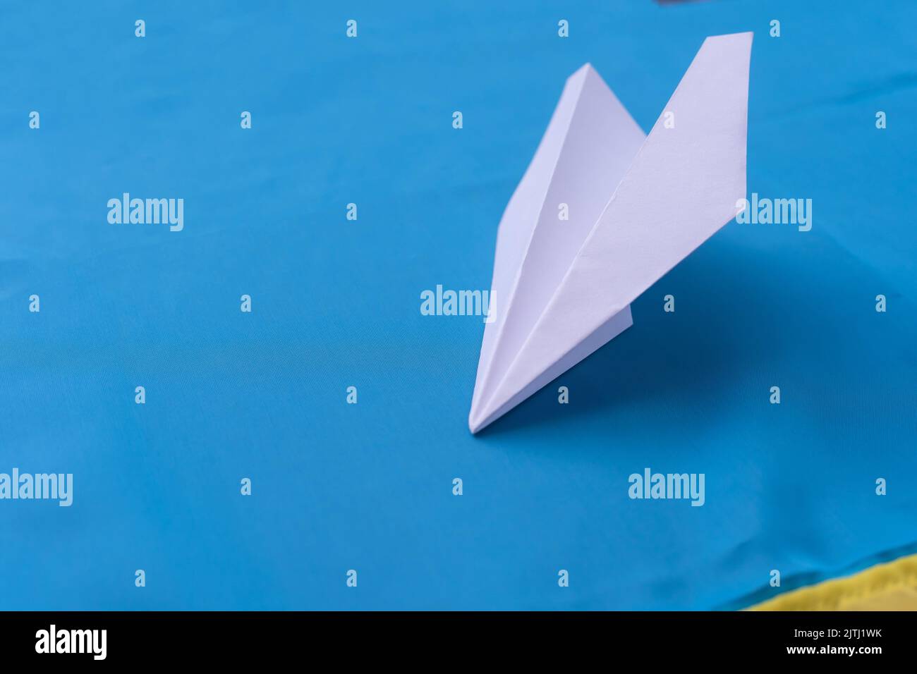 White small paper airplane on a blue background Stock Photo - Alamy
