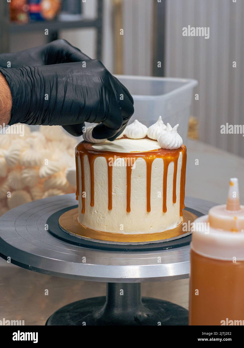 professional baker decorating a chocolate and cream cake with salty ...
