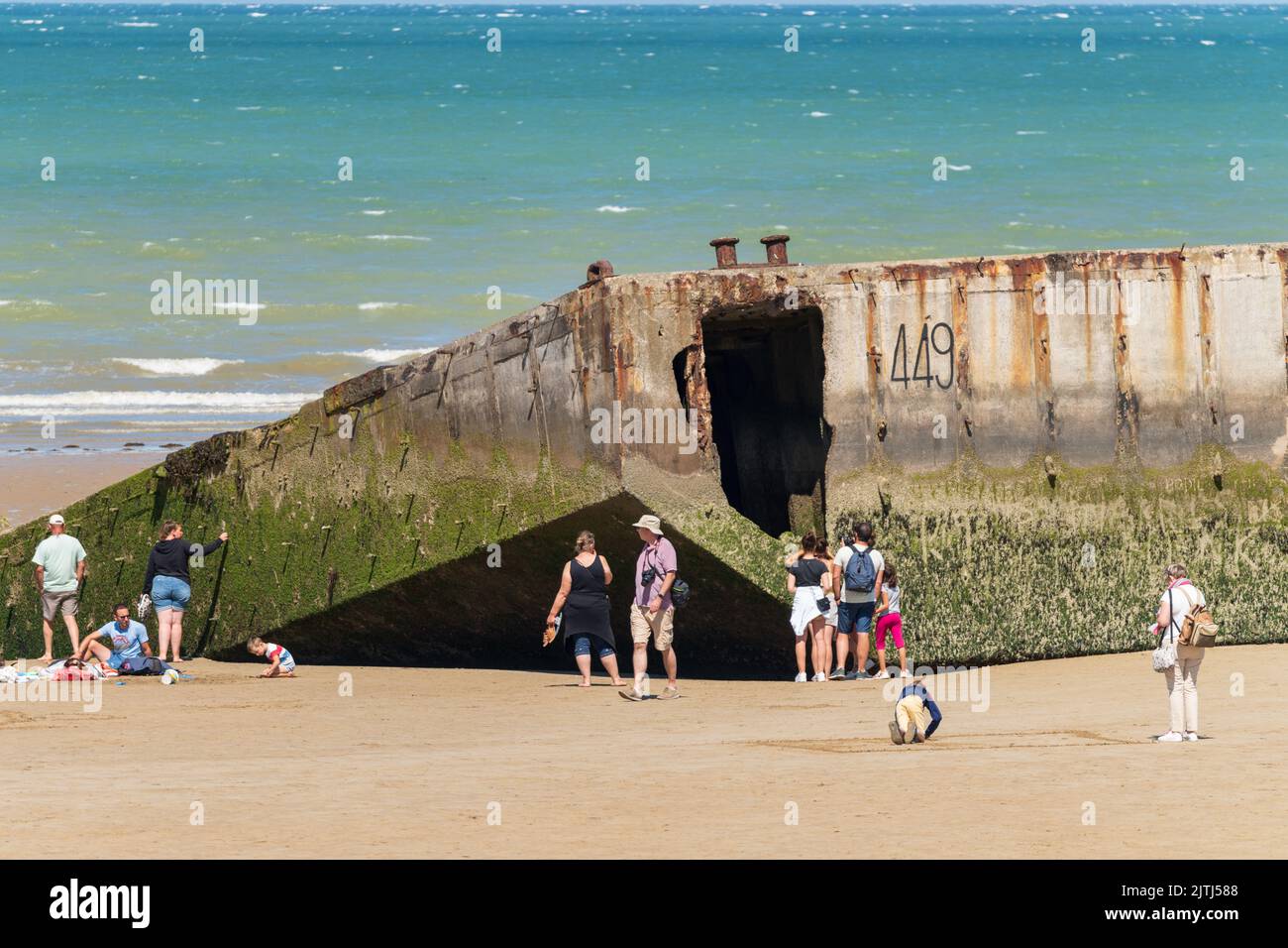 Tourists exploring the remains of the Mulberry harbour on the beach at ...