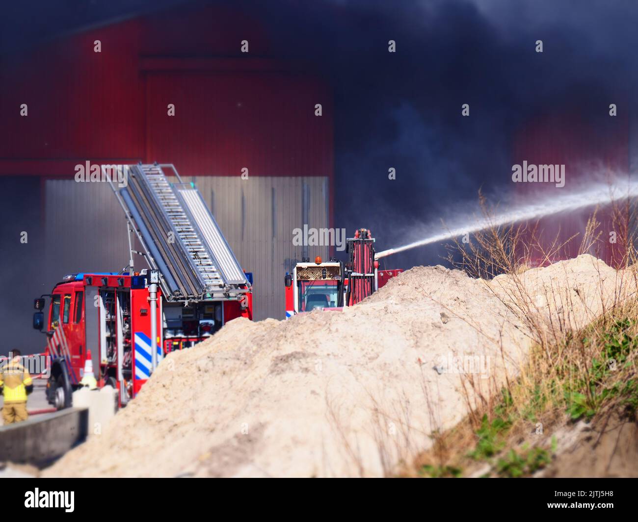 A dusty rock surface with a background of fire trucks and fireman Stock ...