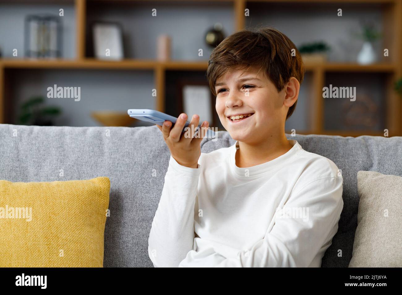 Young cute boy recording voice message on smartphone. Smiling teenager ...