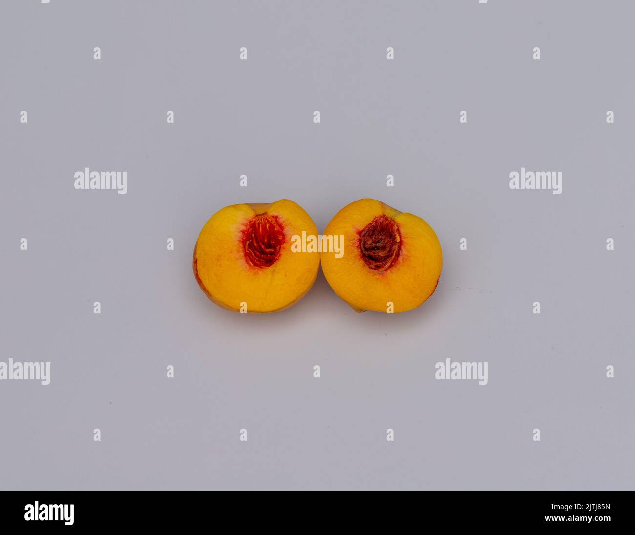 Peach fruit sliced in half on a white isolated background with copy ...