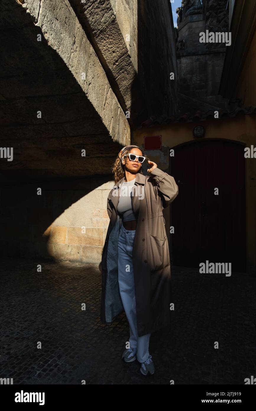 stylish african american woman in trendy accessories and trench coat ...