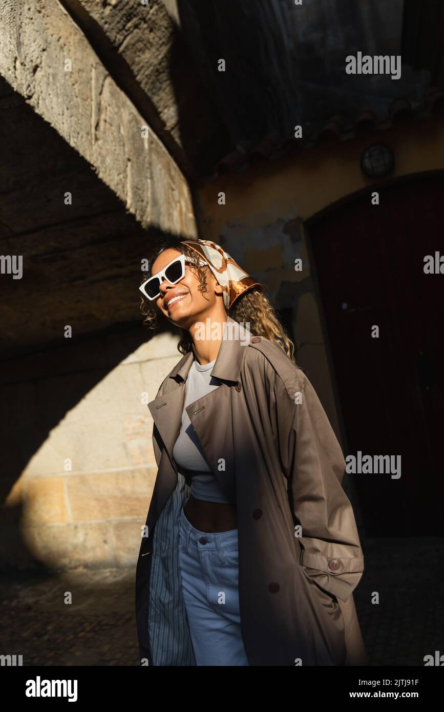 happy african american woman in trendy accessories and trench coat ...