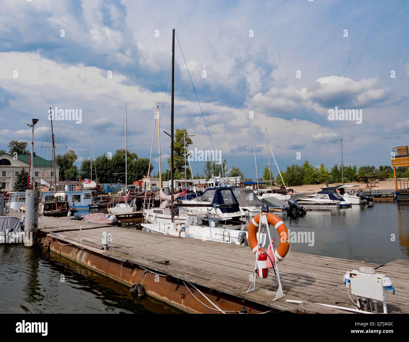 Boats and sailboats moored to a pier in a yacht marina. Summer ...