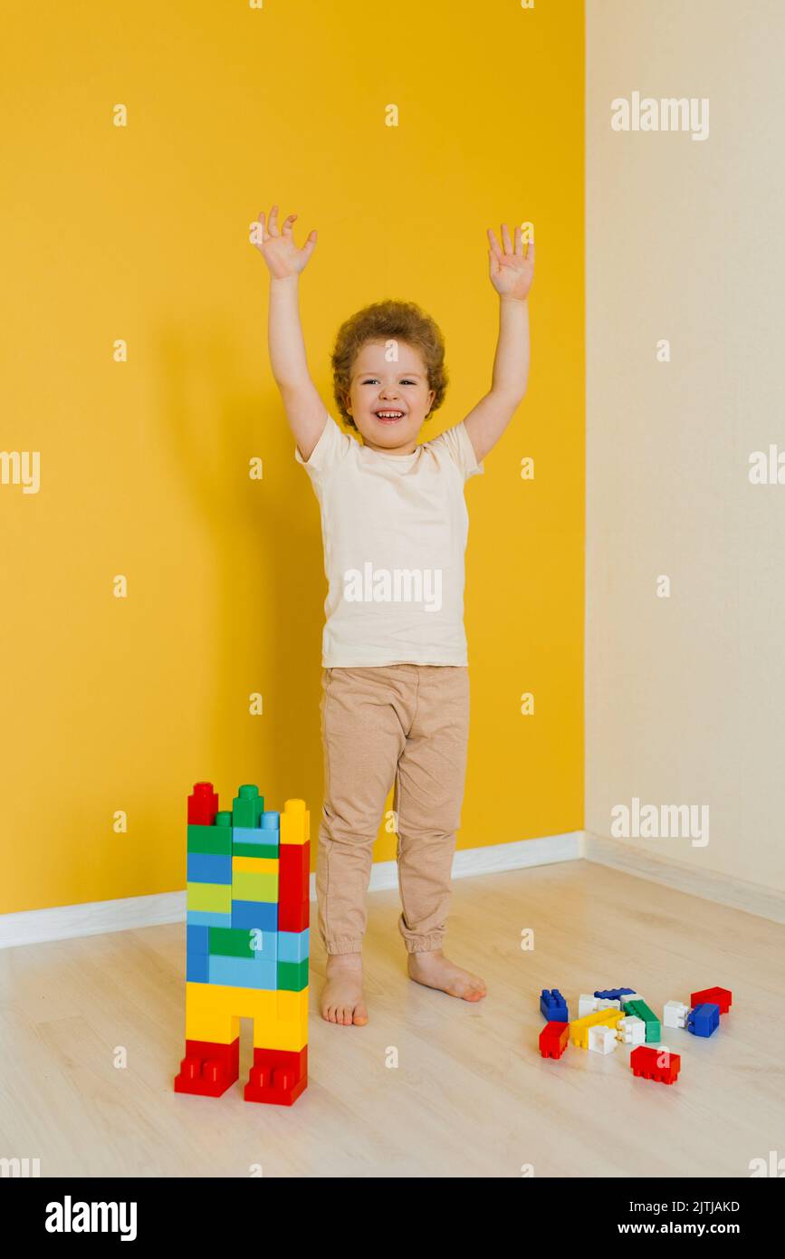 Child is playing with colorful cubes at the table. The kid has fun and ...