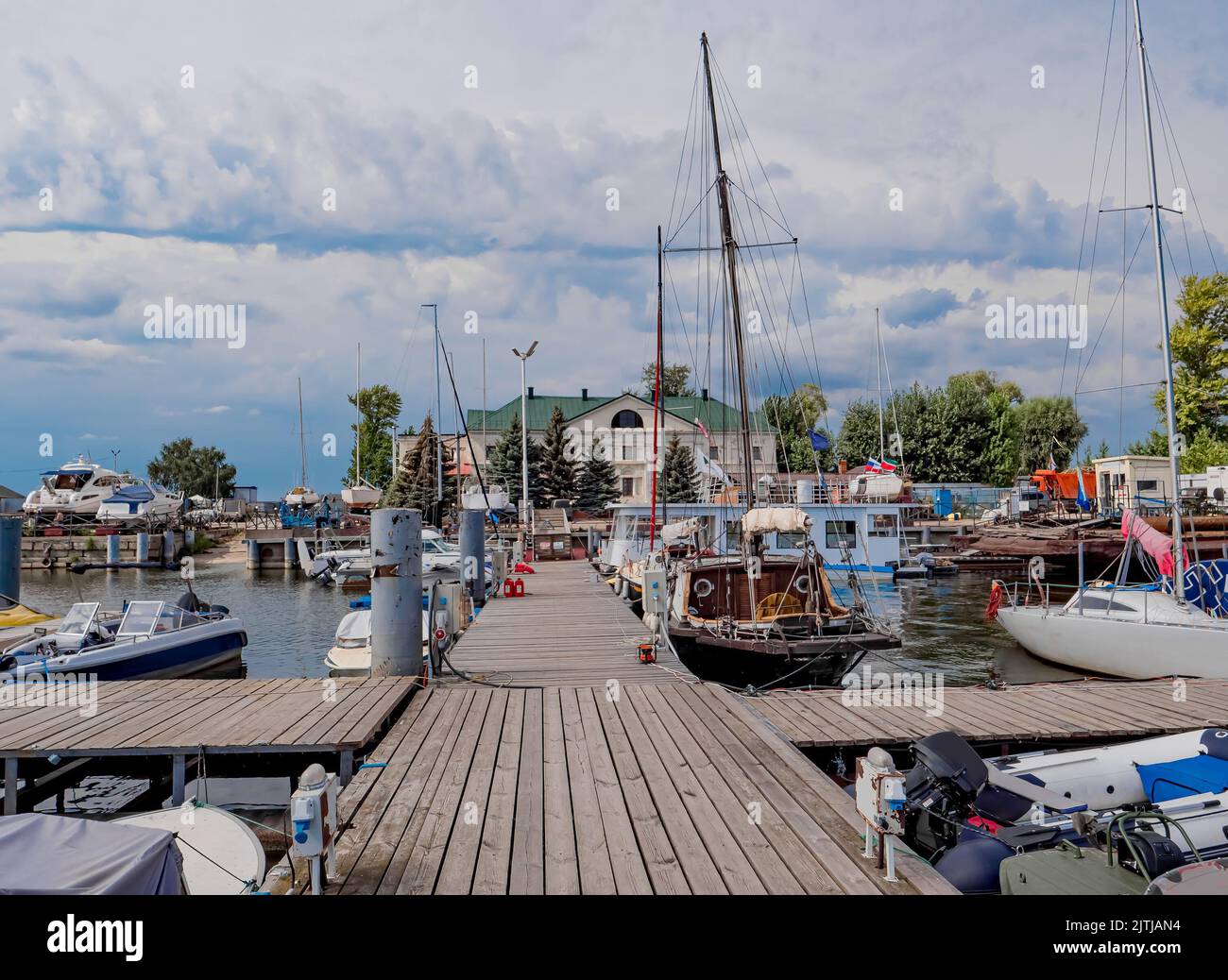 Boats and sailboats moored to a pier in a yacht marina. Summer ...