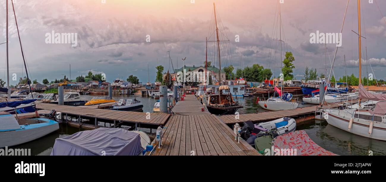 Boats and sailboats moored to a pier in a yacht marina. Summer ...
