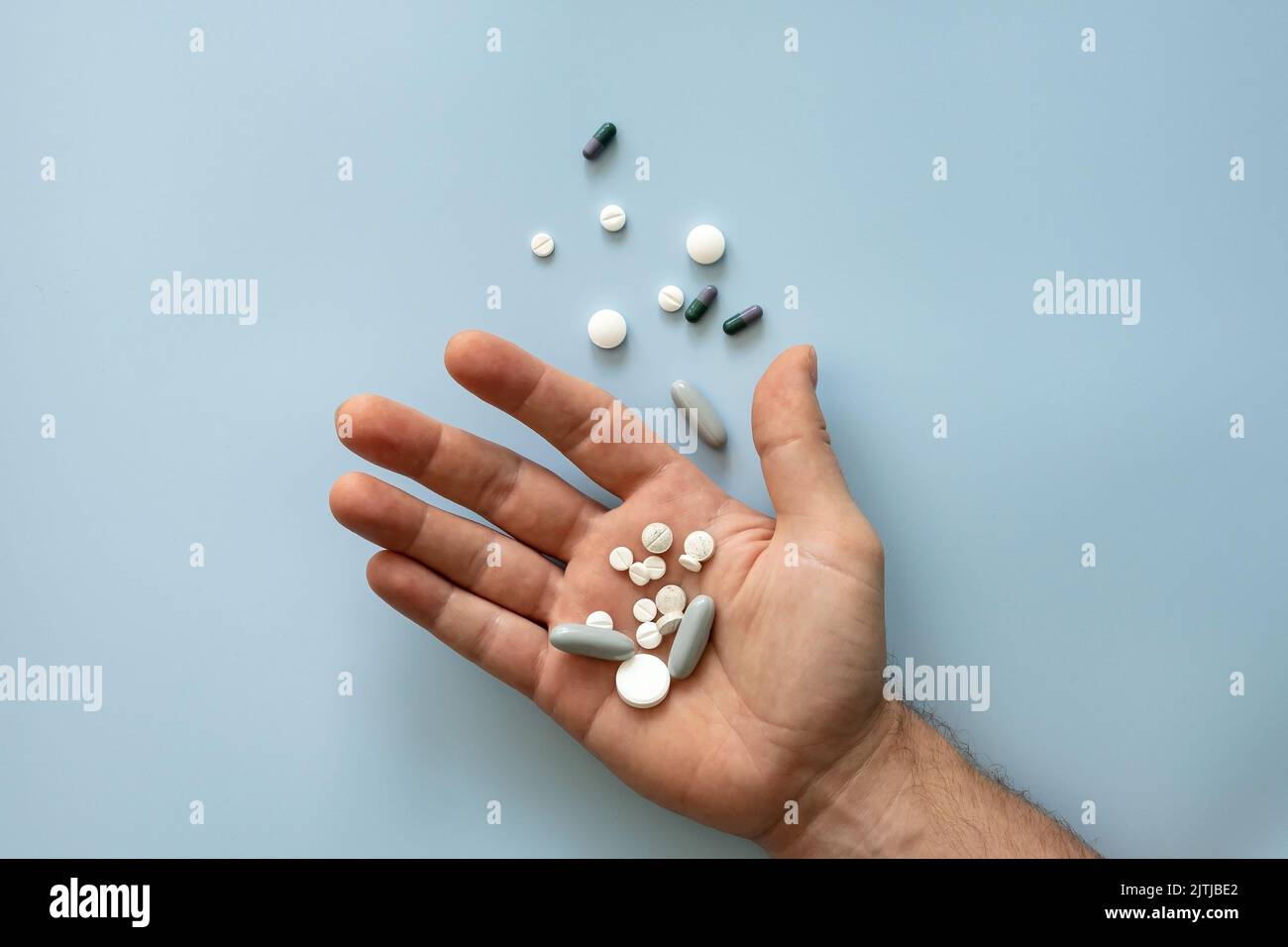 Palm with a handful of various pills on a blue background. Concept of ...