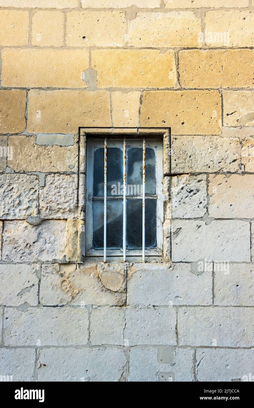 Security bars on a window in a beautiful textures natural stone wall ...