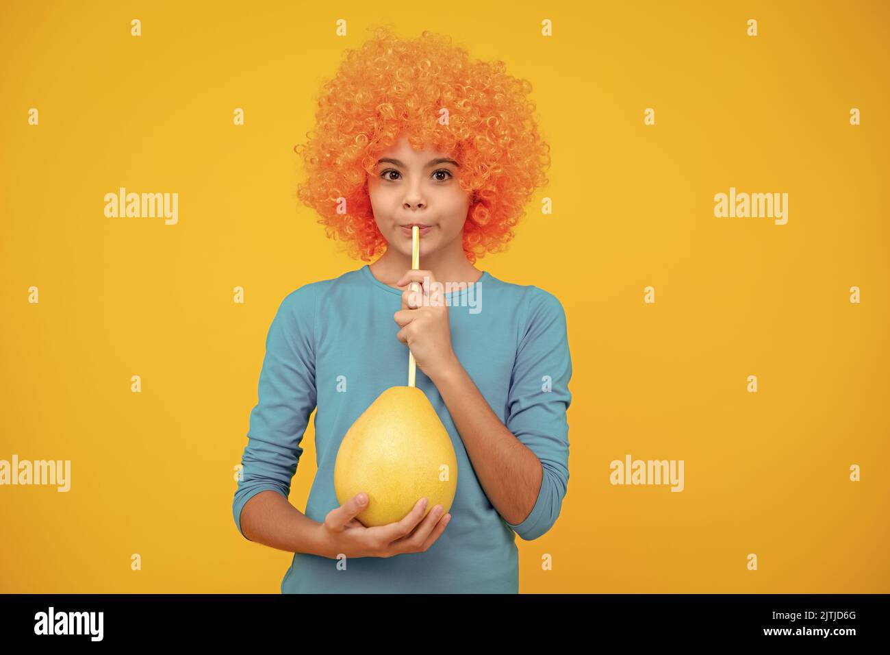 Funny child girl in wig hold big citrus fruit pummelo or pomelo full of ...