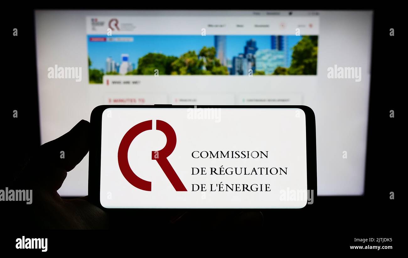 Person holding smartphone with logo of French Commission de Regulation ...