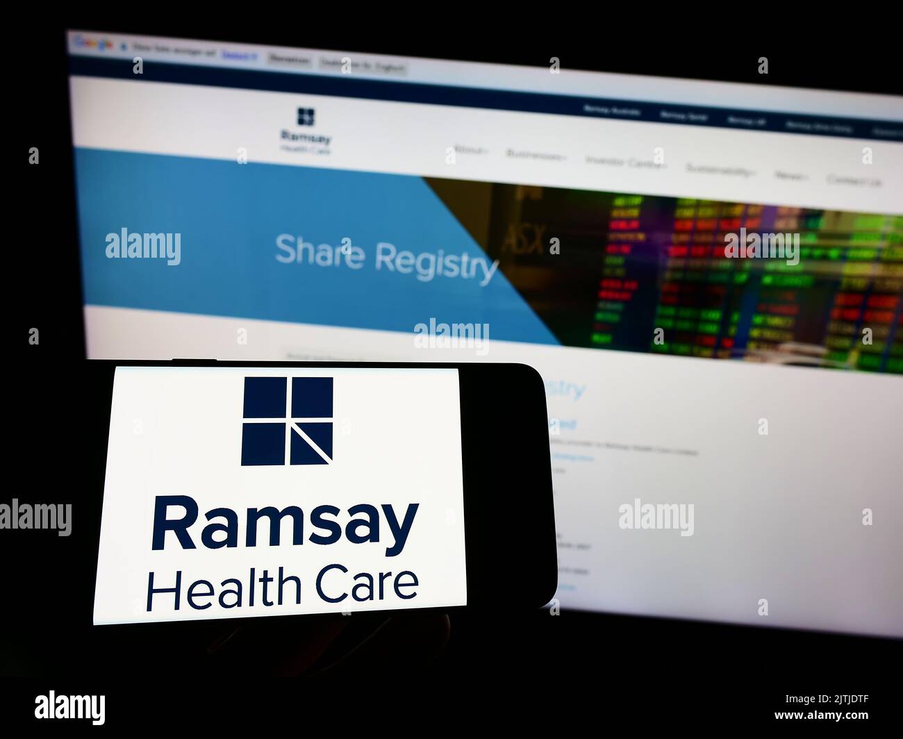 Person holding mobile phone with logo of Australian company Ramsay ...