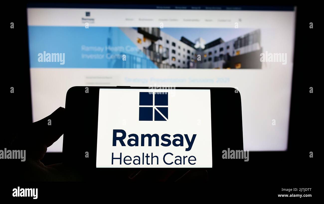 Person holding cellphone with logo of Australian company Ramsay Health ...