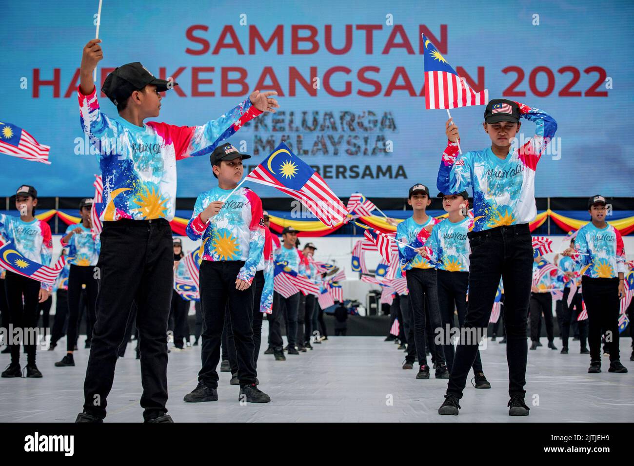 A group of dancers performs while holding the Malaysian flag on the ...