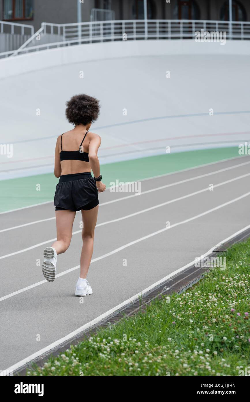 Back view of african american sportswoman running on track of stadium ...